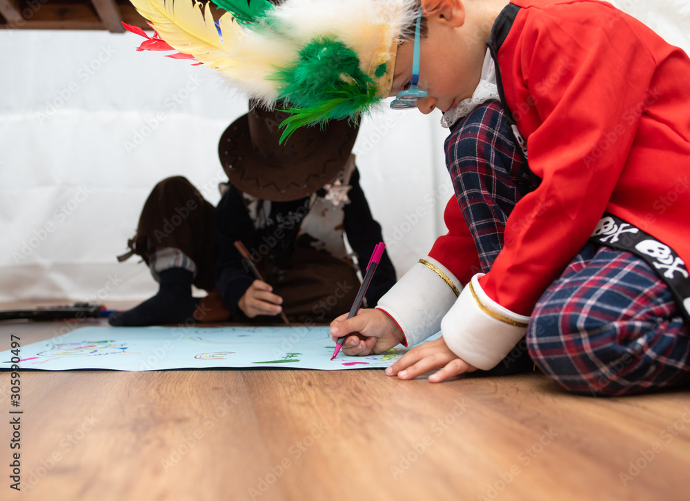 Boy disguised as an Indian drawing with colored pencils on the floor at ...