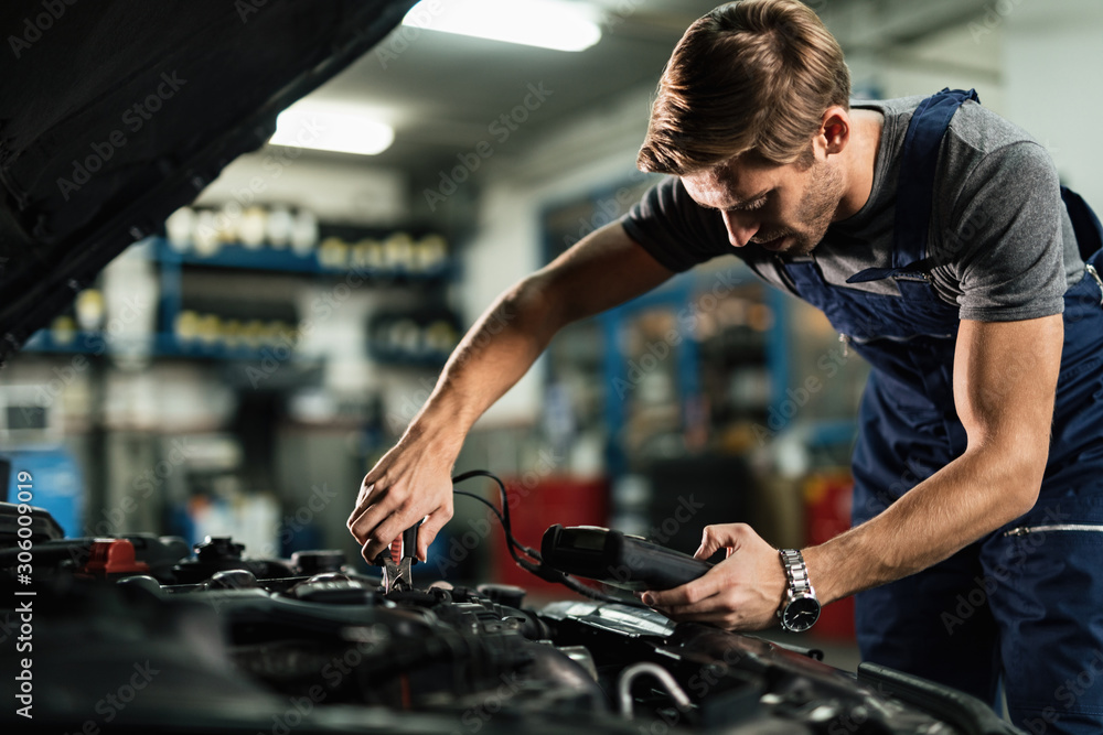 Auto mechanic using diagnostic tool while repairing car engine in a ...