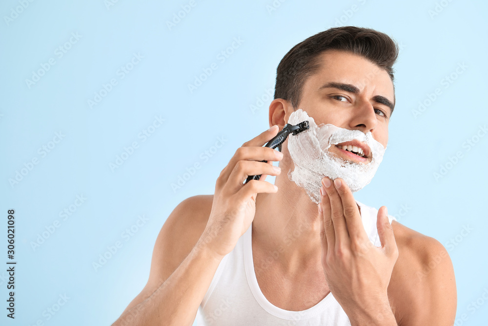 Handsome young man shaving against on color background Stock Photo ...