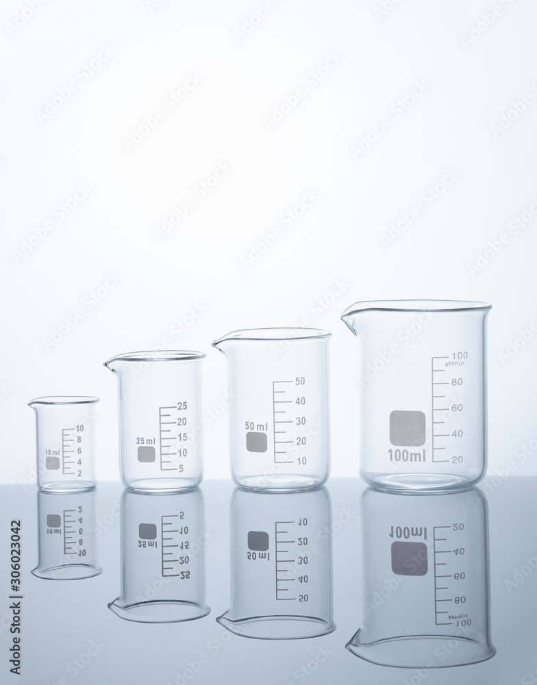 Four empty measuring beakers sitting on a mirror blue surface, glass ...