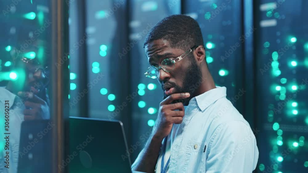 Smart young african engineer diagnosing hardware in rac server cabinet ...