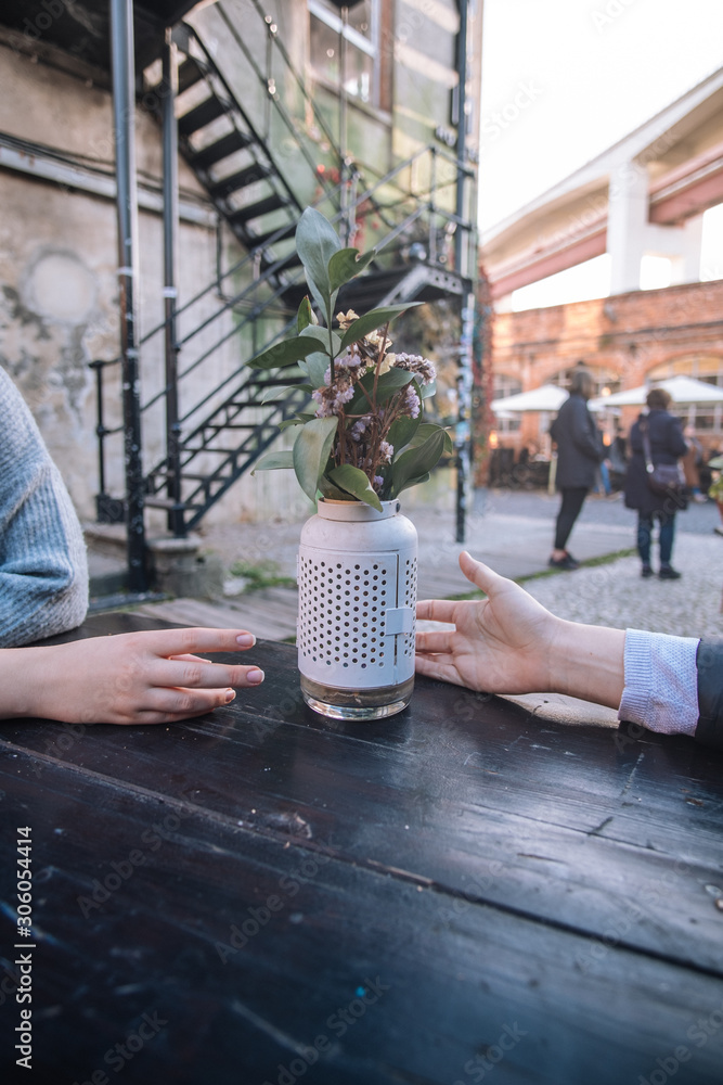 Two girls having a conversation outside in a bar, detail of their hands ...