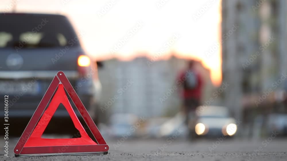 Red emergency stop sign behind broken blurred car with blinking lights ...