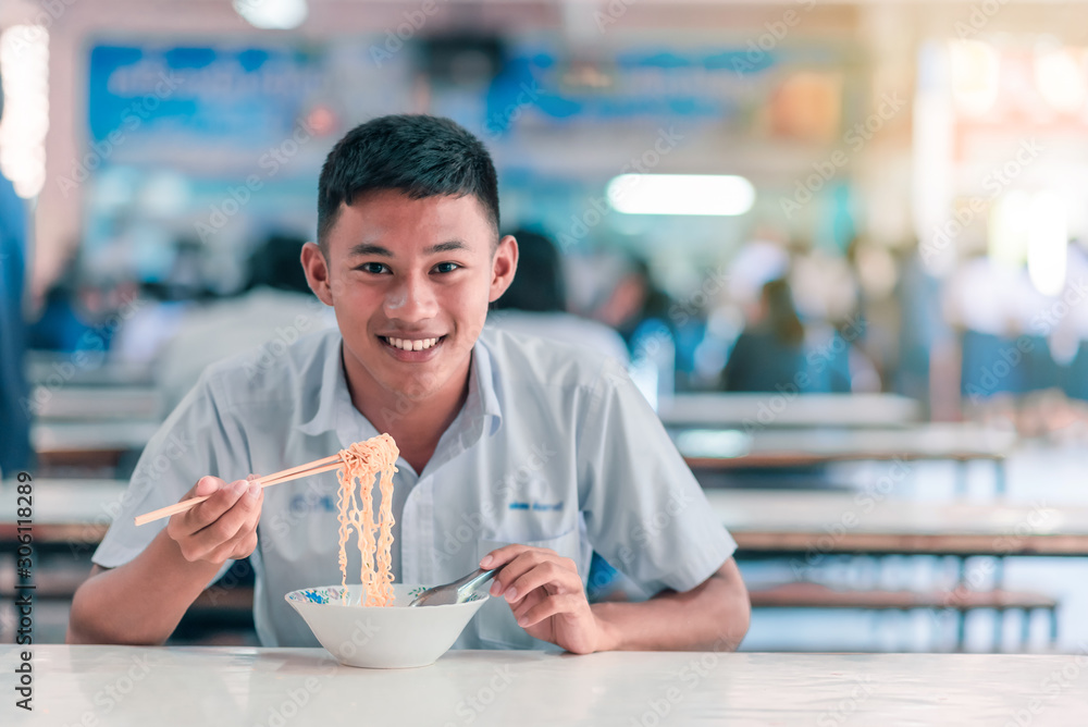 A smiling Asian male high school student in white uniform is eating ...