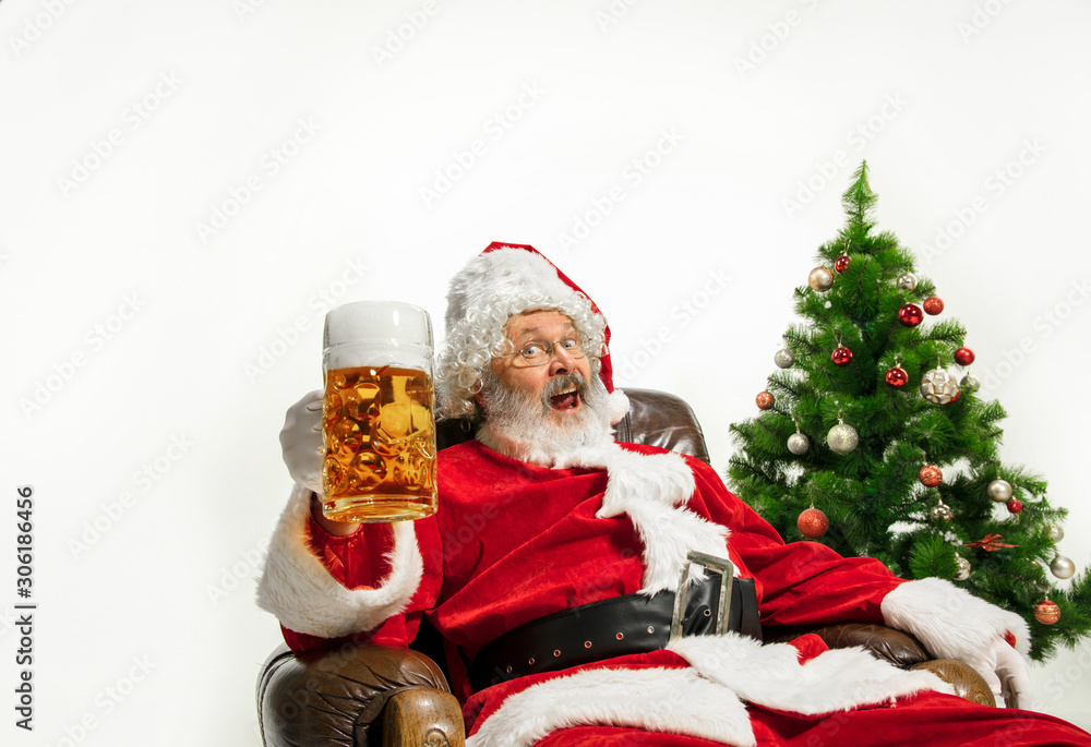 Santa Claus drinking beer near the Christmas tree, congratulating ...