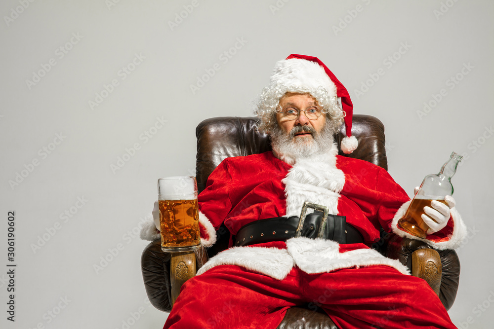 Santa Claus drinking beer sitting on armchair, congratulating, looks ...