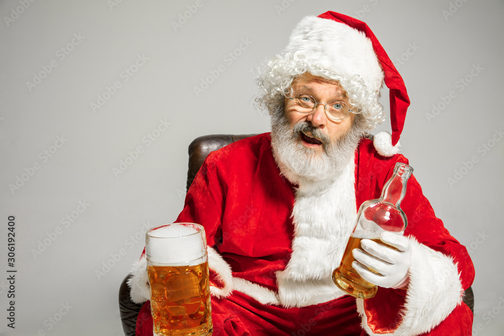Santa Claus drinking beer sitting on armchair, congratulating, looks ...