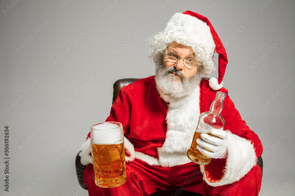 Santa Claus drinking beer sitting on armchair, congratulating, looks ...