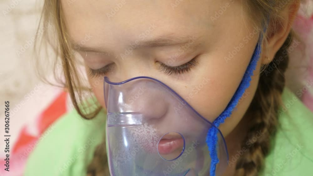 child with a tablet is sick and breathes through an inhaler. close-up ...