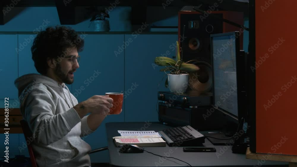 Young adult office worker sitting at desk in modern workspace late at ...