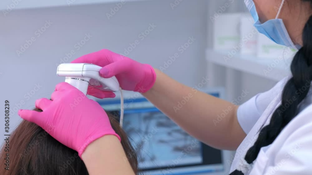 Doctor trichologist examines woman patient's hairs using trichoscope in ...