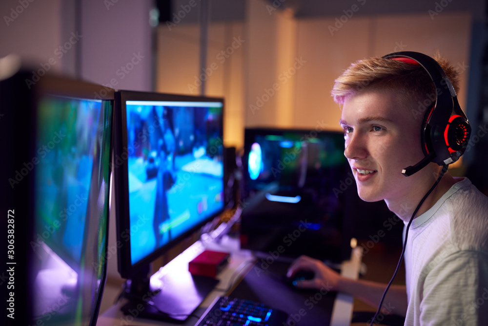 Teenage Boy Wearing Headset Gaming At Home Using Dual Computer Screens ...