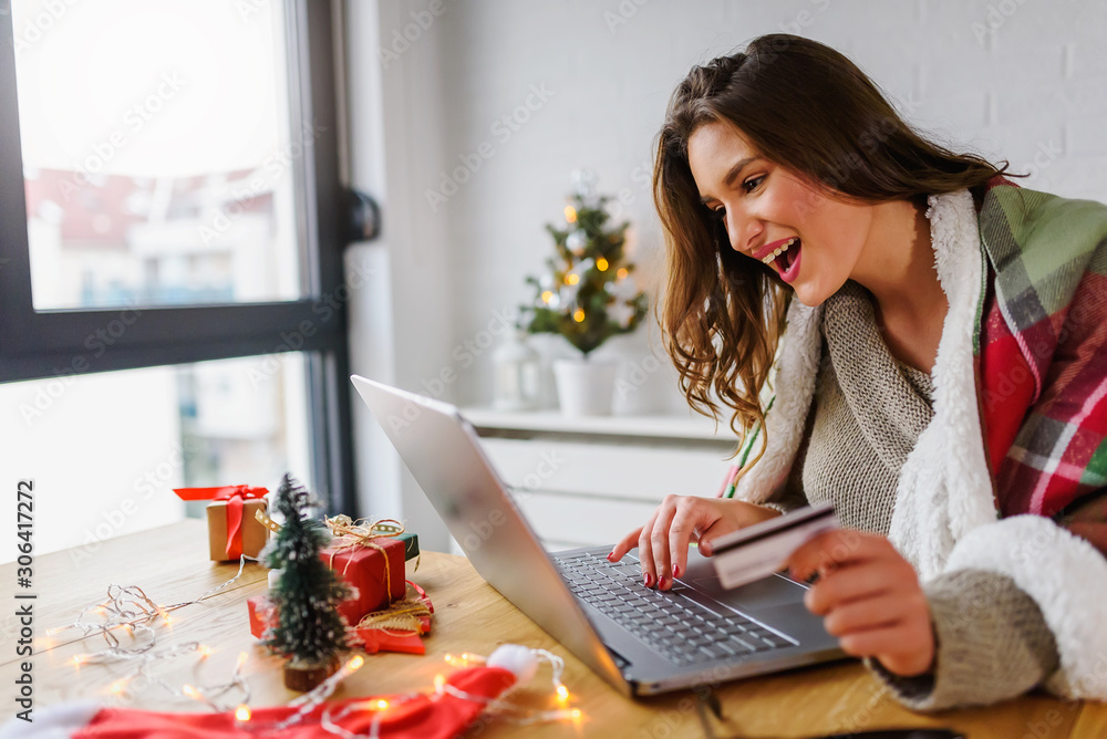 Young woman buying online at home for winter holidays using laptop ...