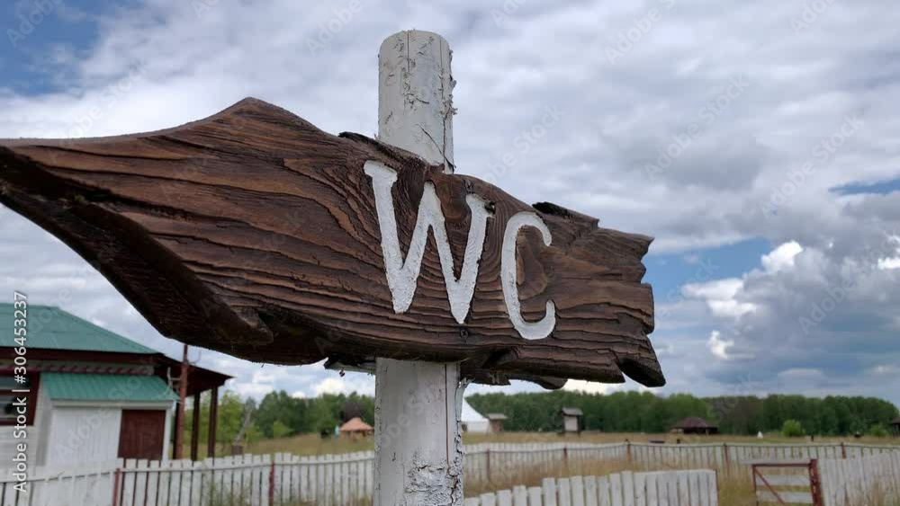 An outdoor wooden arrow signboard WC, public restroom sign in a ...