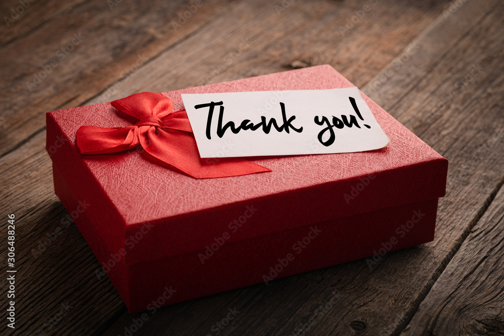 Red gift box and label with the words thank you on a wooden background ...