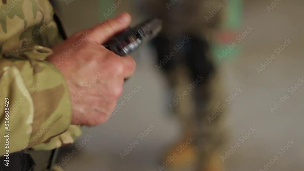 close-up. a man turns a pistol in his right hand, holds a magazine for ...