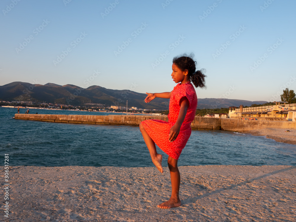 Jamaican European ethnicity little girl dancing on the sea pier in a ...
