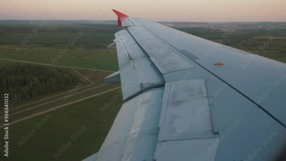 Jet plane landing at airport. View from window of the plane to the wing ...