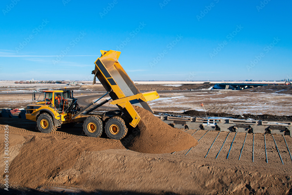 Rock Truck dumping load of sandy granular material on galvanized metal ...
