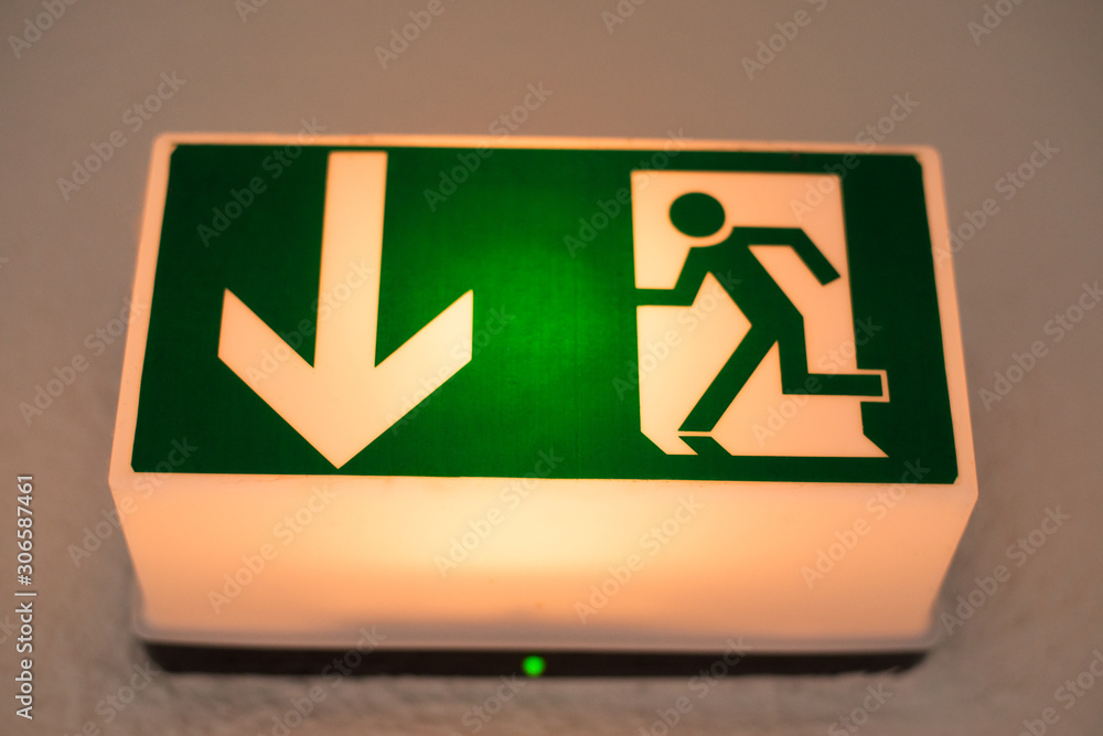 Illuminated green exit sign in a public place. Green emergency exit ...