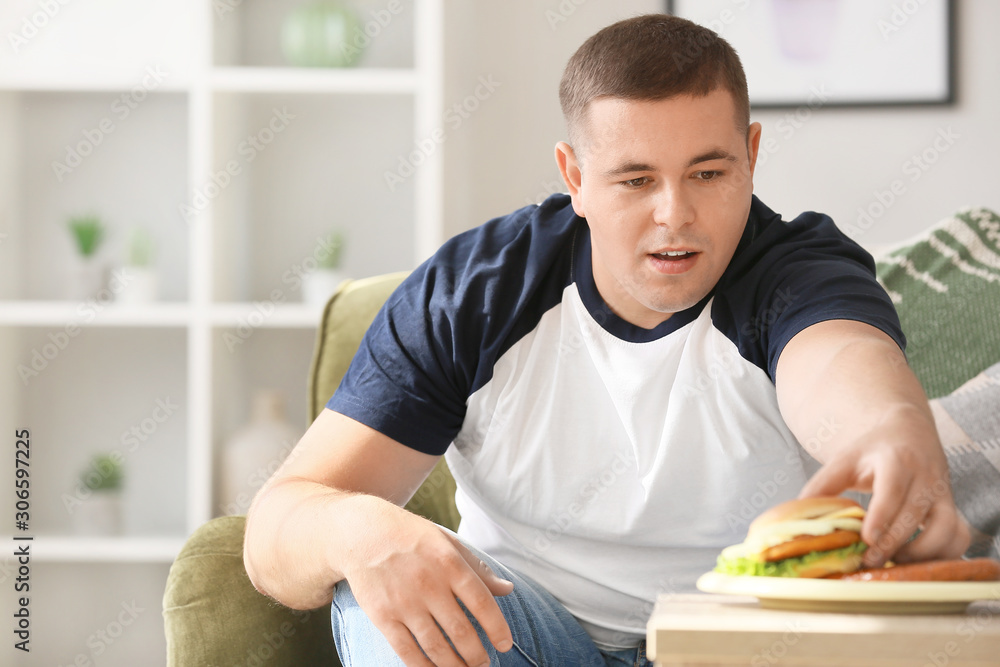 Overweight man eating unhealthy food at home Stock Photo | Adobe Stock