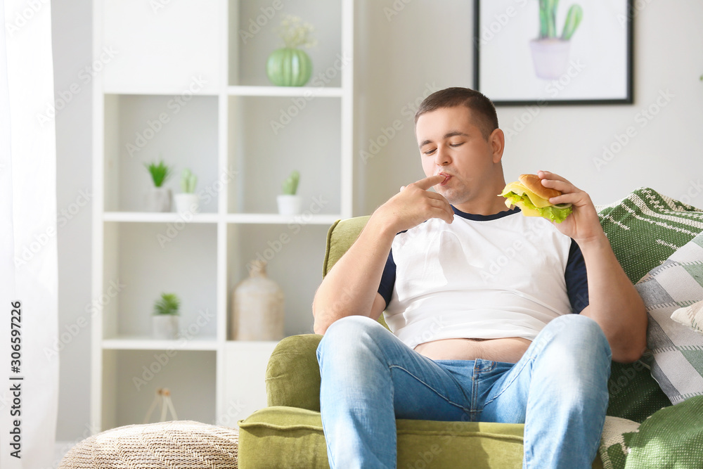Overweight man eating unhealthy food at home Stock Photo | Adobe Stock