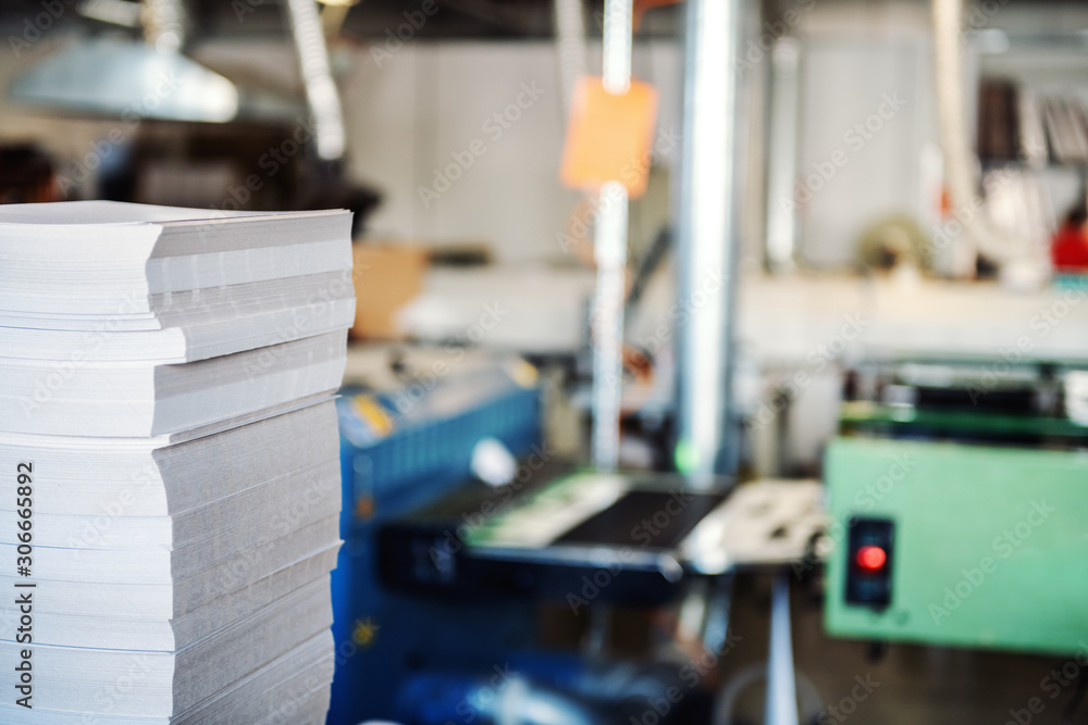 Picture of printing shop interior. Selective focus on pile of sheets ...