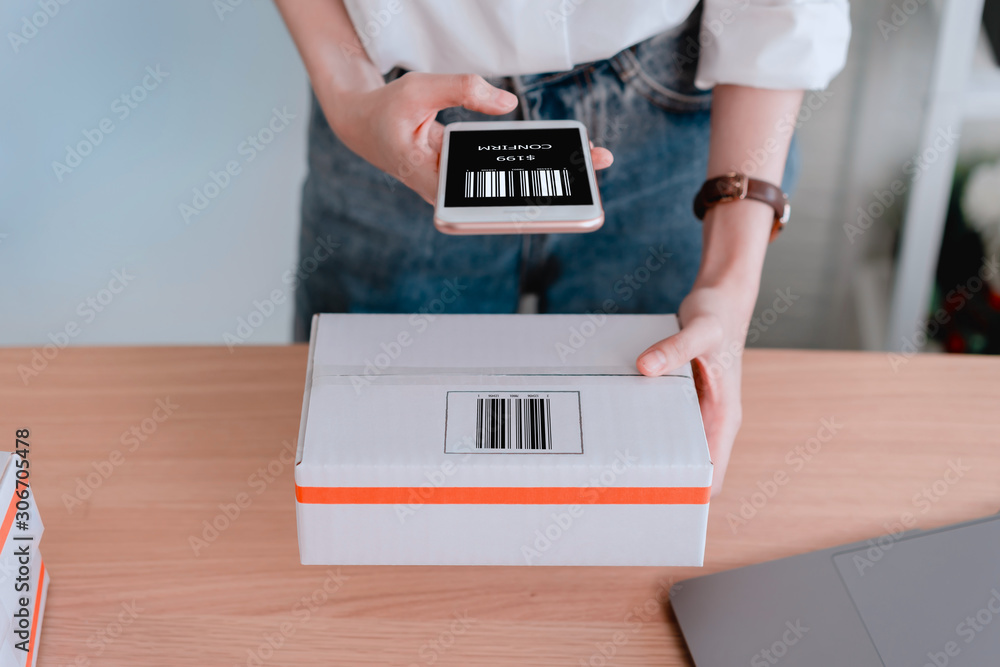 Young woman owner using smartphone for checking product on stock scan ...