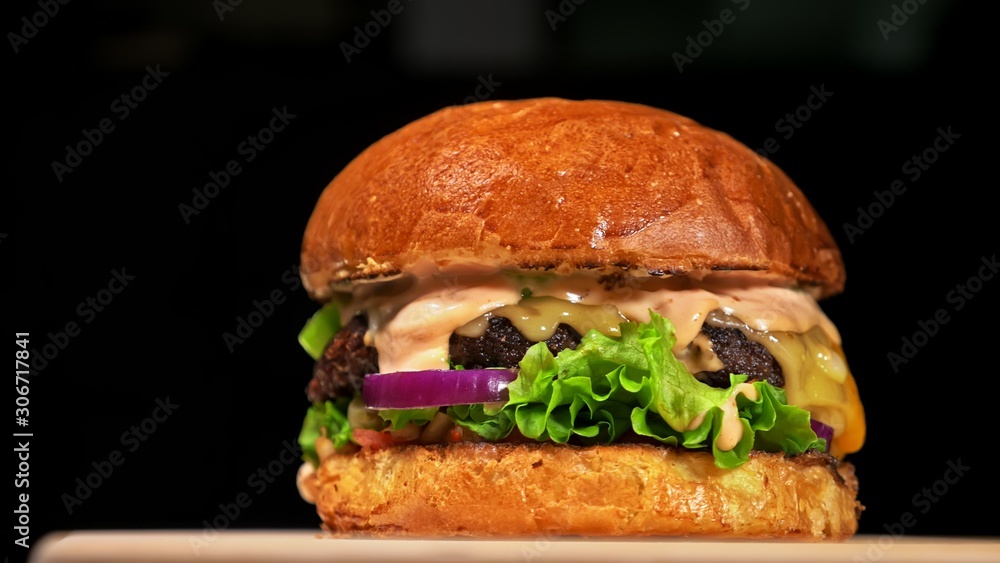 Craft burger is cooking on black background. Consist: red sauce salsa ...
