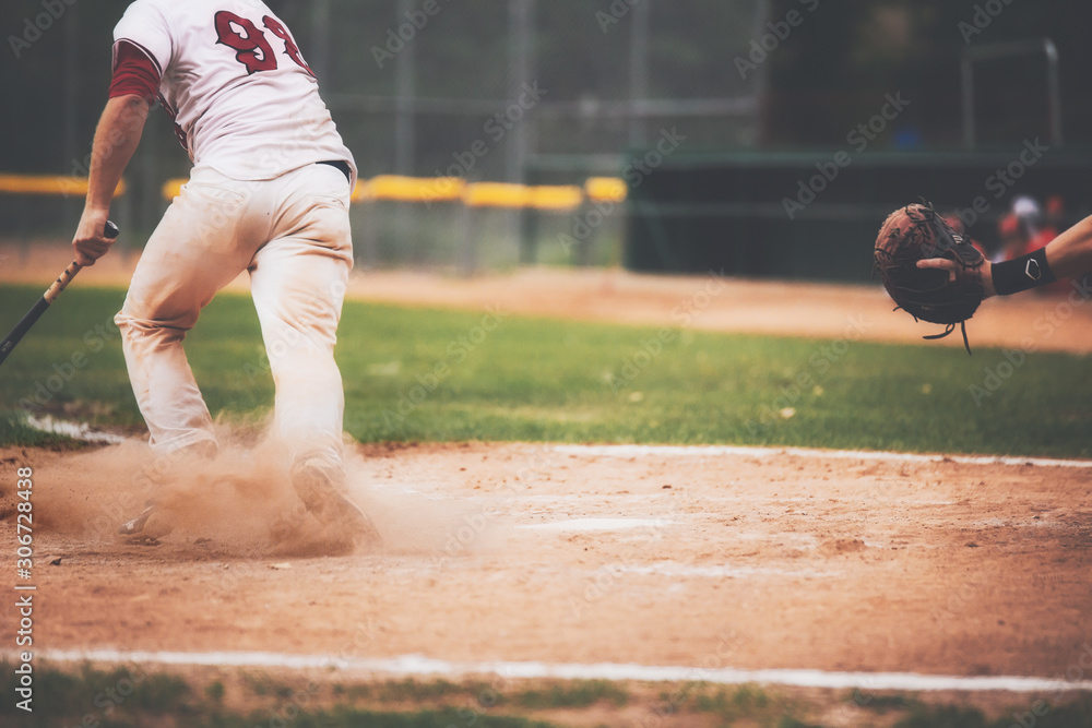 The bottom half of a male baseball player with a cloud of red dust ...