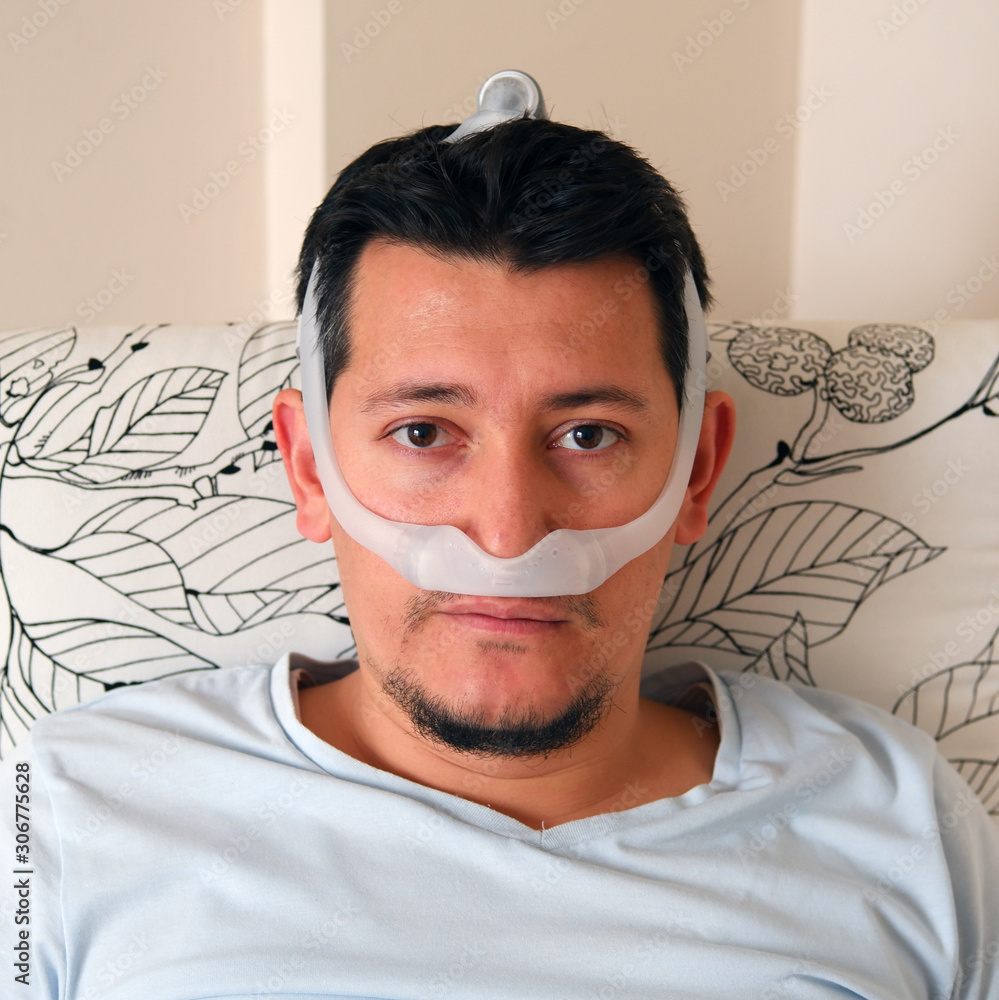 Healthy young man wearing under the nose nasal mask and using Cpap ...