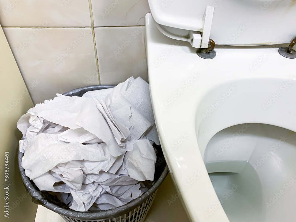 Overflowing trash can, dustbin full of used toilet paper near the ...