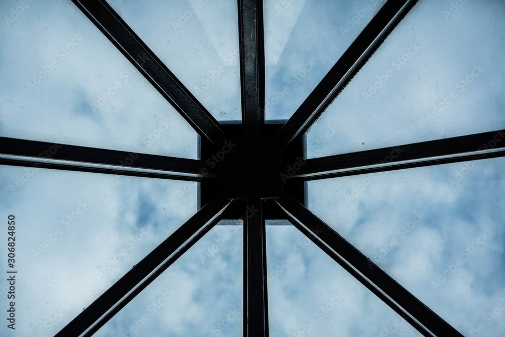 symmetrical line of glass roof silhouette rays, background is blue sky ...