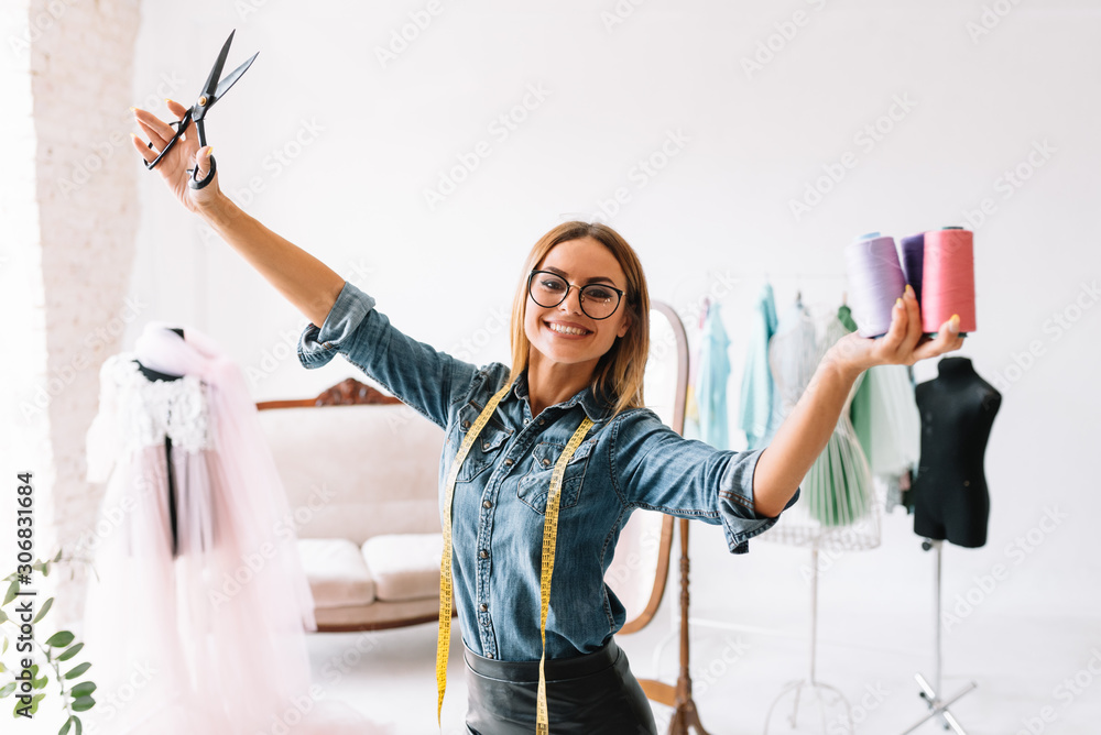 Portrait of female dress maker standing at her atelier and holding ...