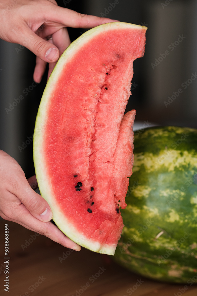Hands holding a watermelon. The watermelon was cut and separated. Stock ...