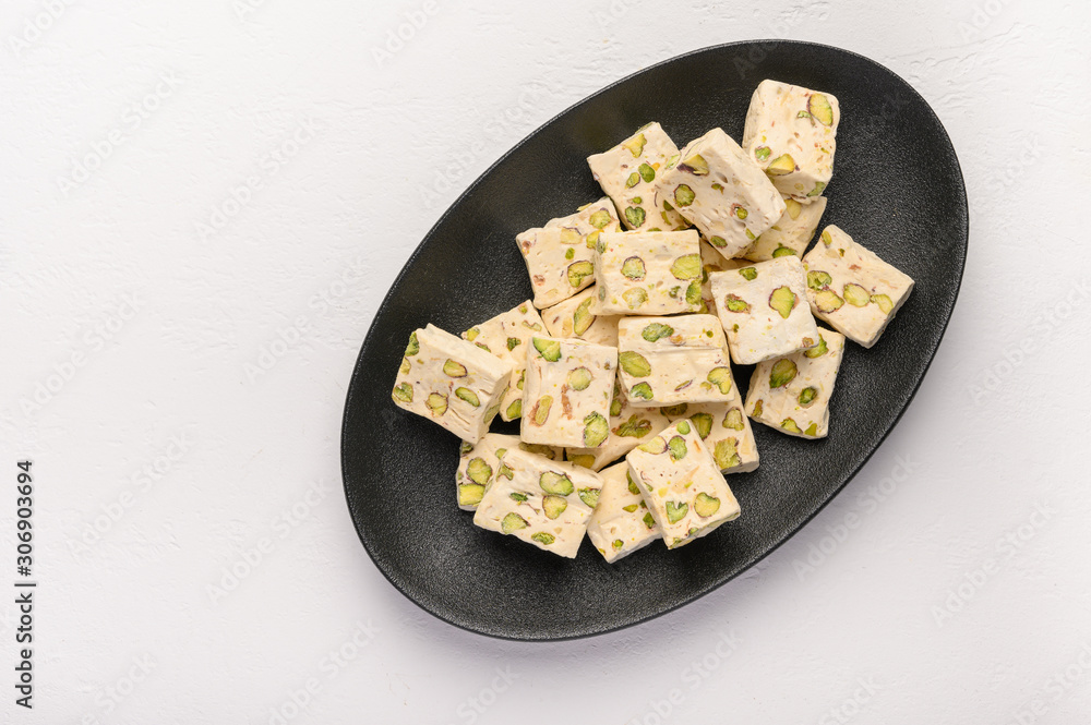 Eastern Arabic nougat sweetness with pistachios on a ceramic plate on a ...