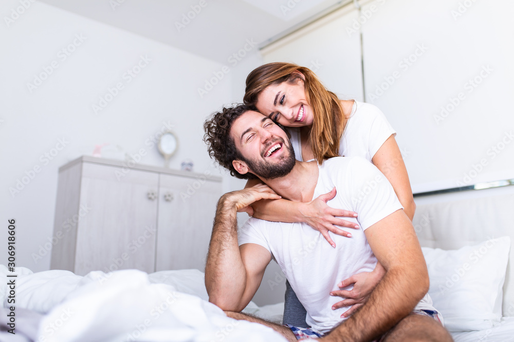 Woman embracing her partner in bed, Happy couple in bed showing ...