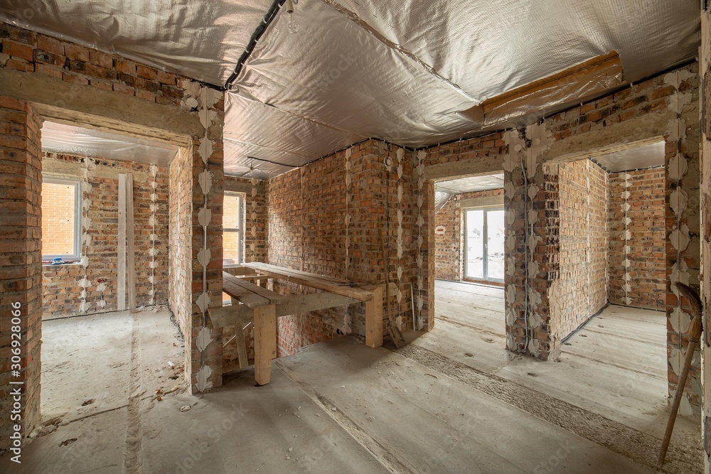Interior of unfinished brick house with concrete floor and bare walls ...