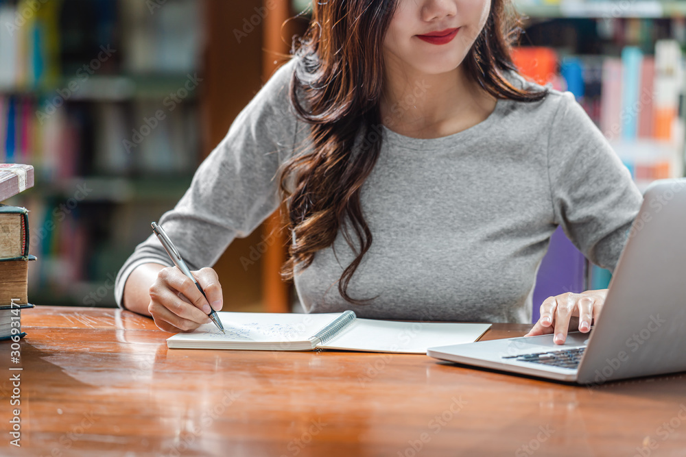 Closeup Asian young Student hand writing homework and using technology ...
