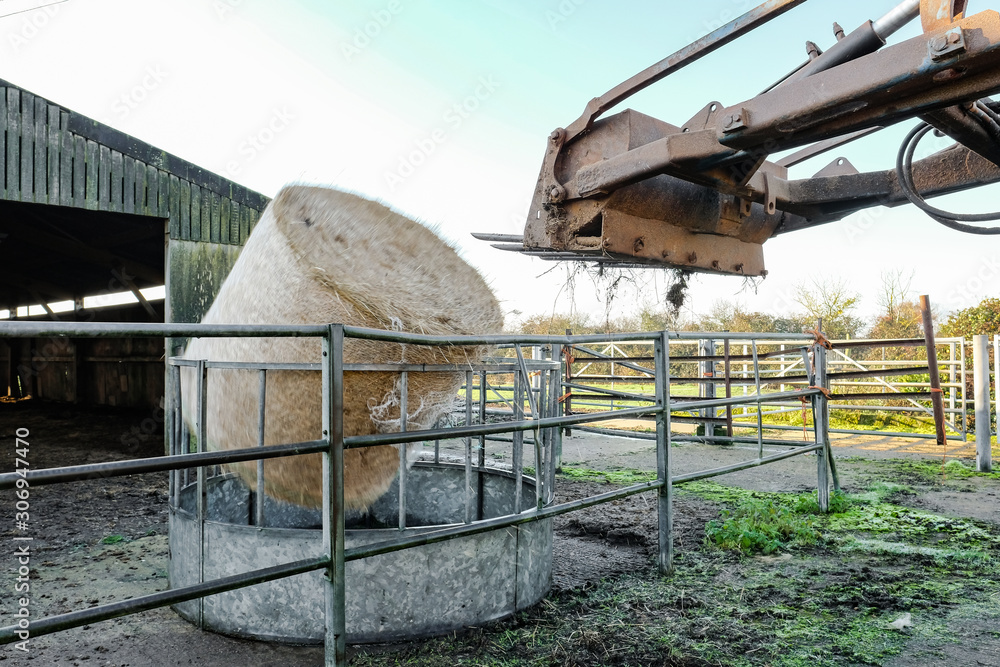 Blurred view of a large bale of hay seen bring dropped from a farm ...