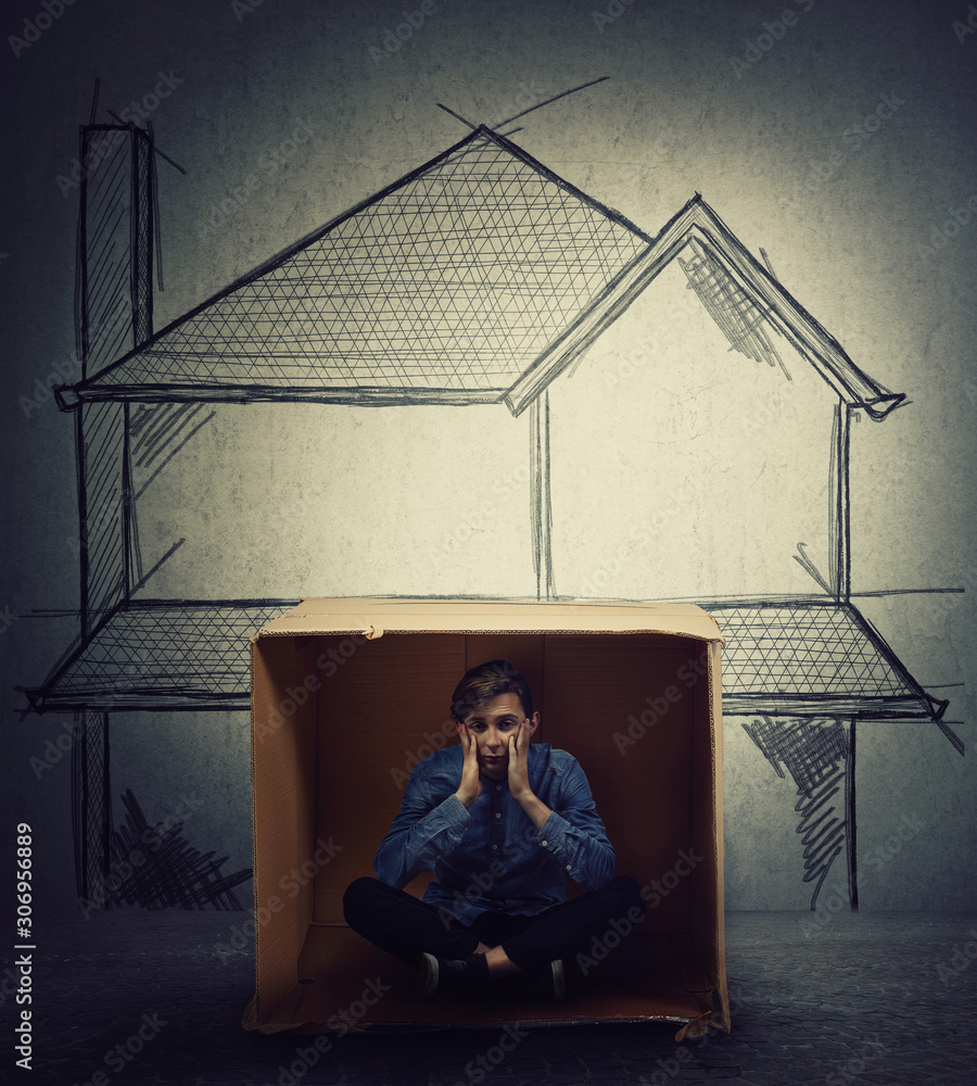 Stressed teenage boy sitting inside a cardboard box hut, imagine a big ...