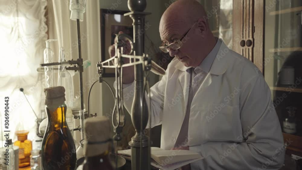 Portrait of old bald Caucasian man checking ancient flasks, containers ...