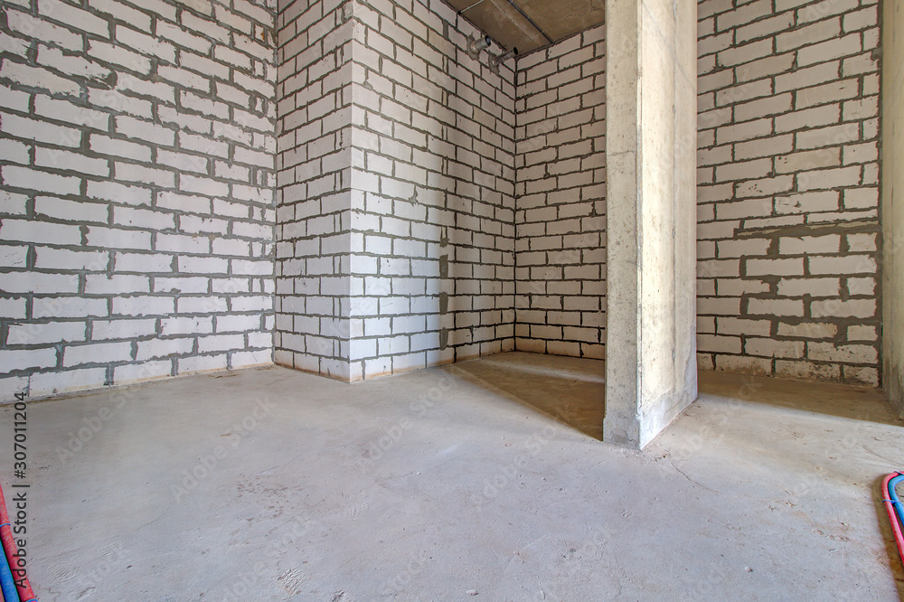 Monolithic brick basement wall. heating pipes lie on floor. New empty ...