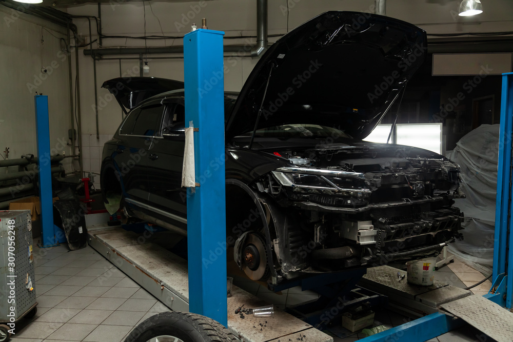 Used car with an open hood and trunk witout bumper raised on a lift for ...