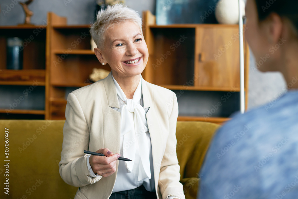 Positive charming middle aged blonde woman recruiter making notes ...