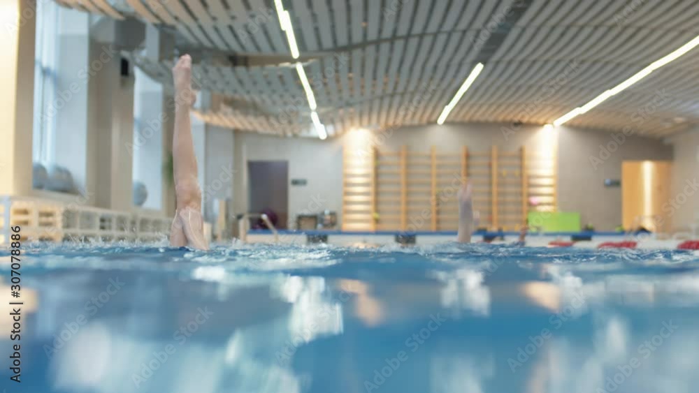 Two young professional swimmers training legs stretching and synchronic ...