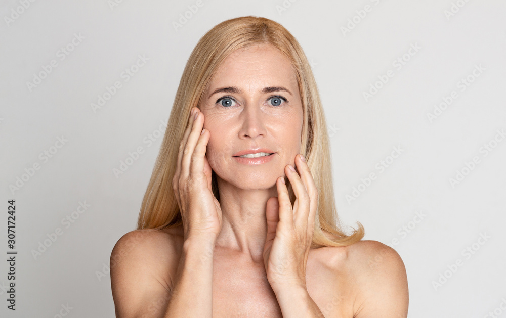 Beautiful middle-aged woman with bare shoulders touching her face Stock ...