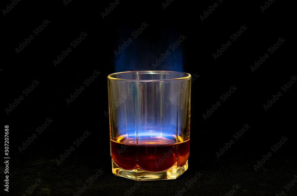 Alcoholic drink burns with a blue flame on a black background, whiskey ...
