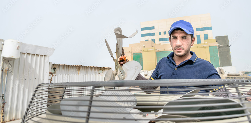 professional electricians are repairing fan wings of a compressor of a ...
