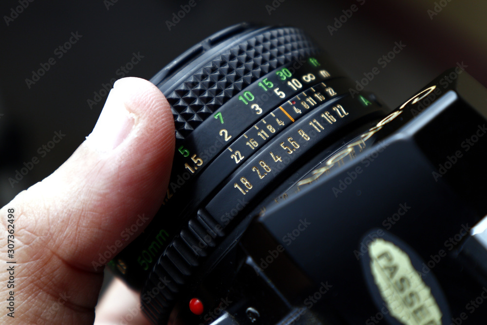 Hand holding the focusing ring on the lens of an old and vintage 35mm ...